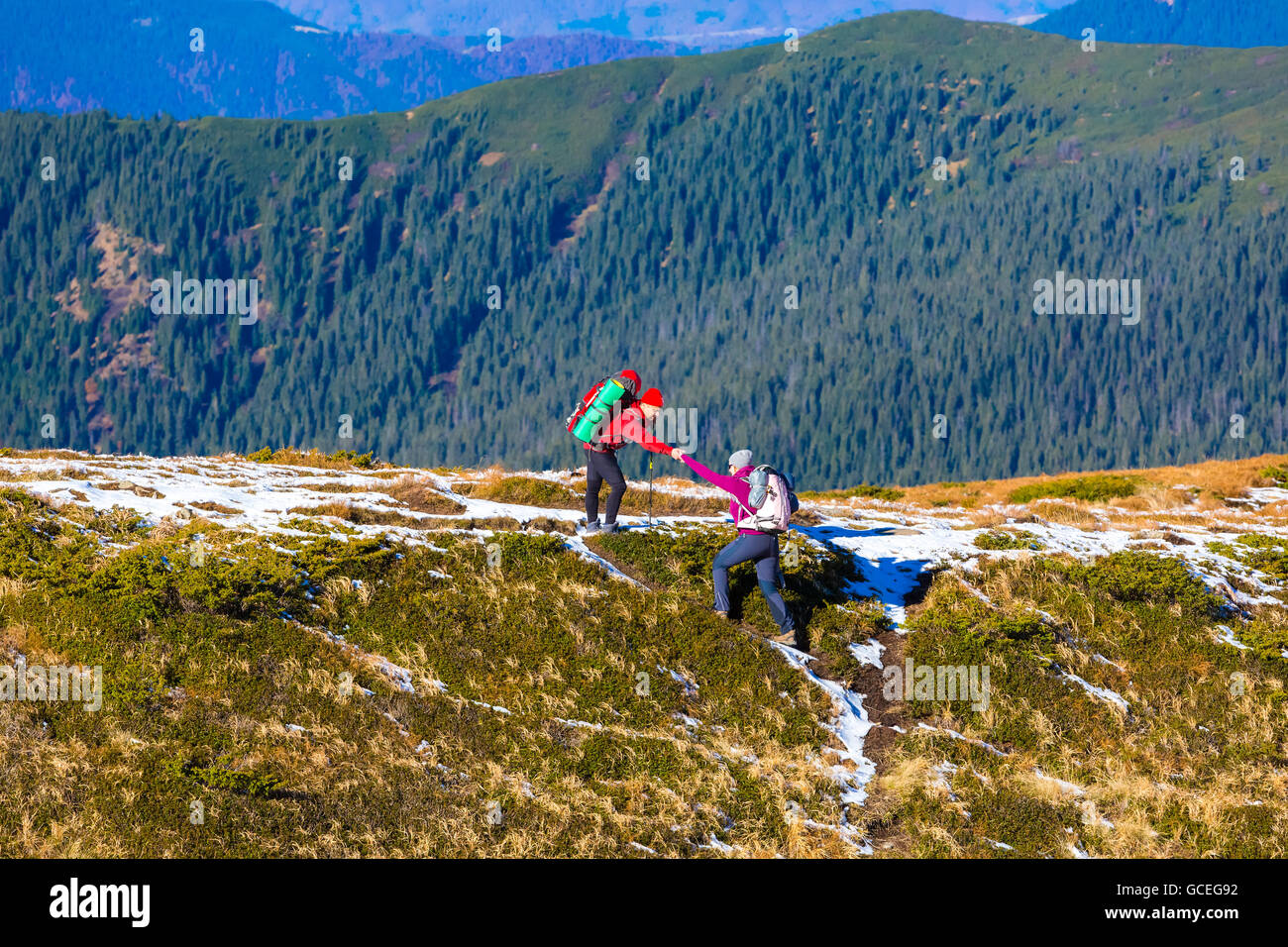 Man helping Woman to climb on steep Mountain Ridge Stock Photo - Alamy