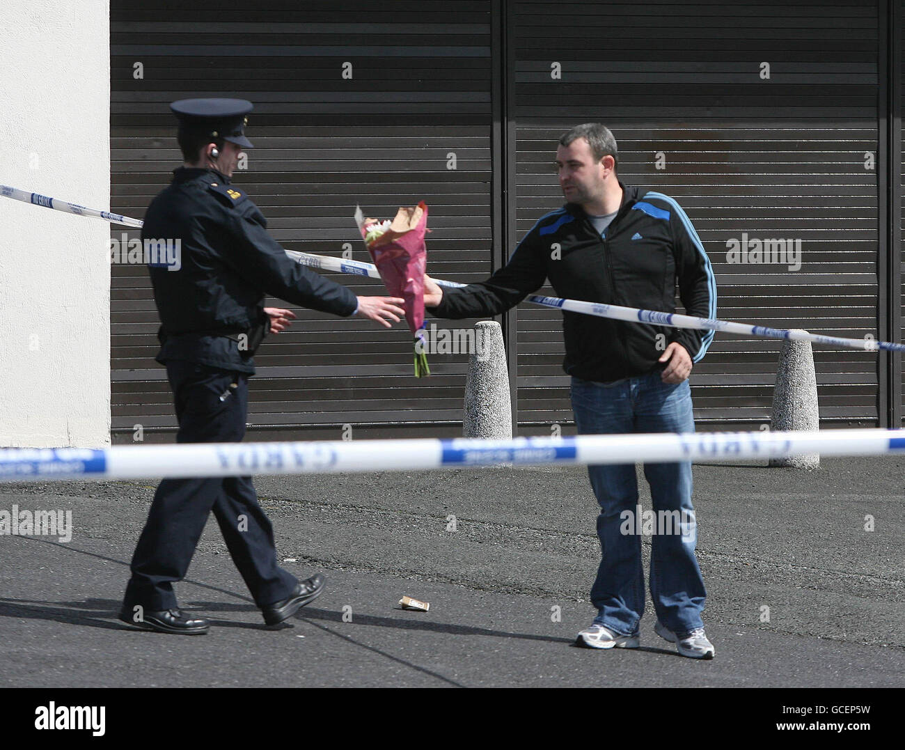 A member of the public passes flowers to a Garda outside the Faussagh ...