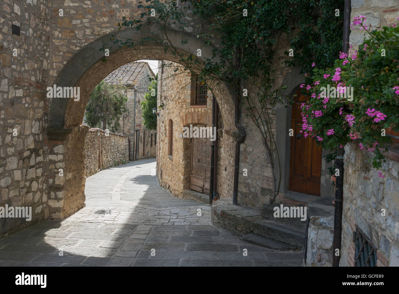 Walkway past stone walls and an archway by residential buildings ...