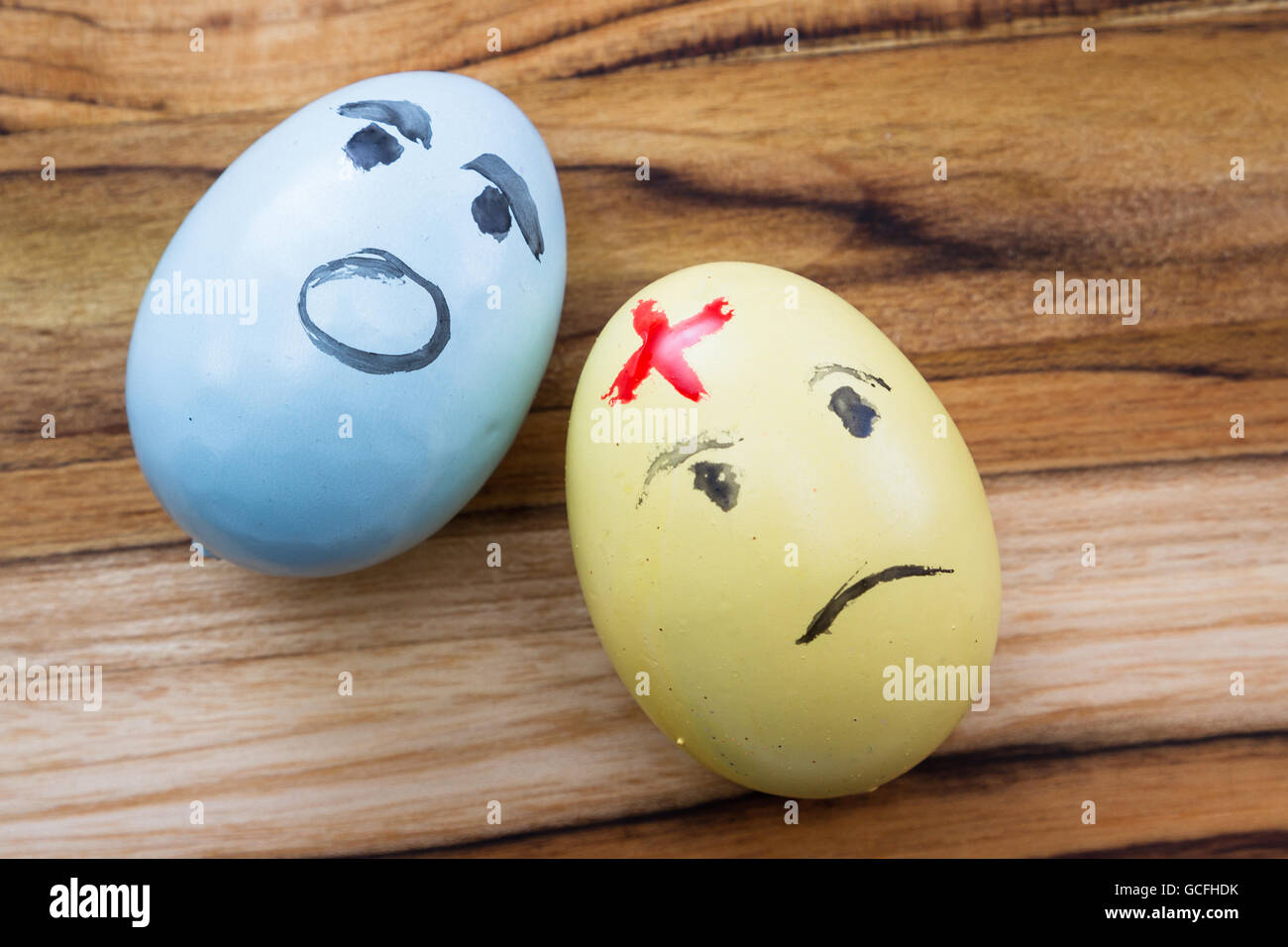 hand painted easter eggs with sad and scarred expressions on a wooden ...