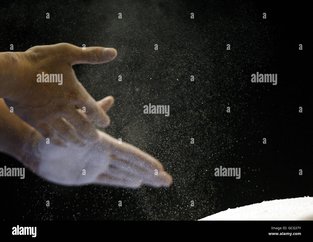 General view of a gymnast adding chalk to there hands for extra grip ...