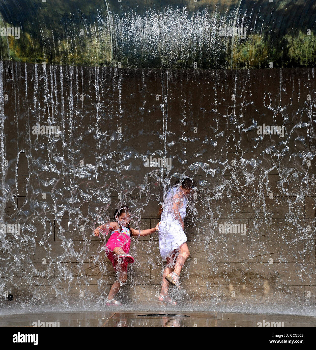 Two young people playing in a fountain waterfall, Derby City centre ...