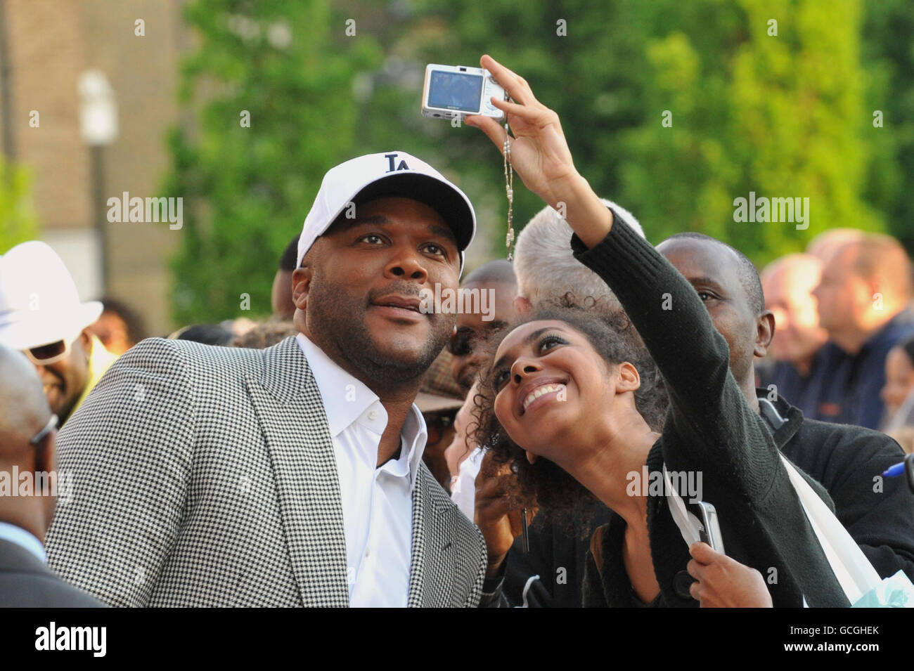 Tyler Perry has his picture taken with a fan as he arrives for the ...