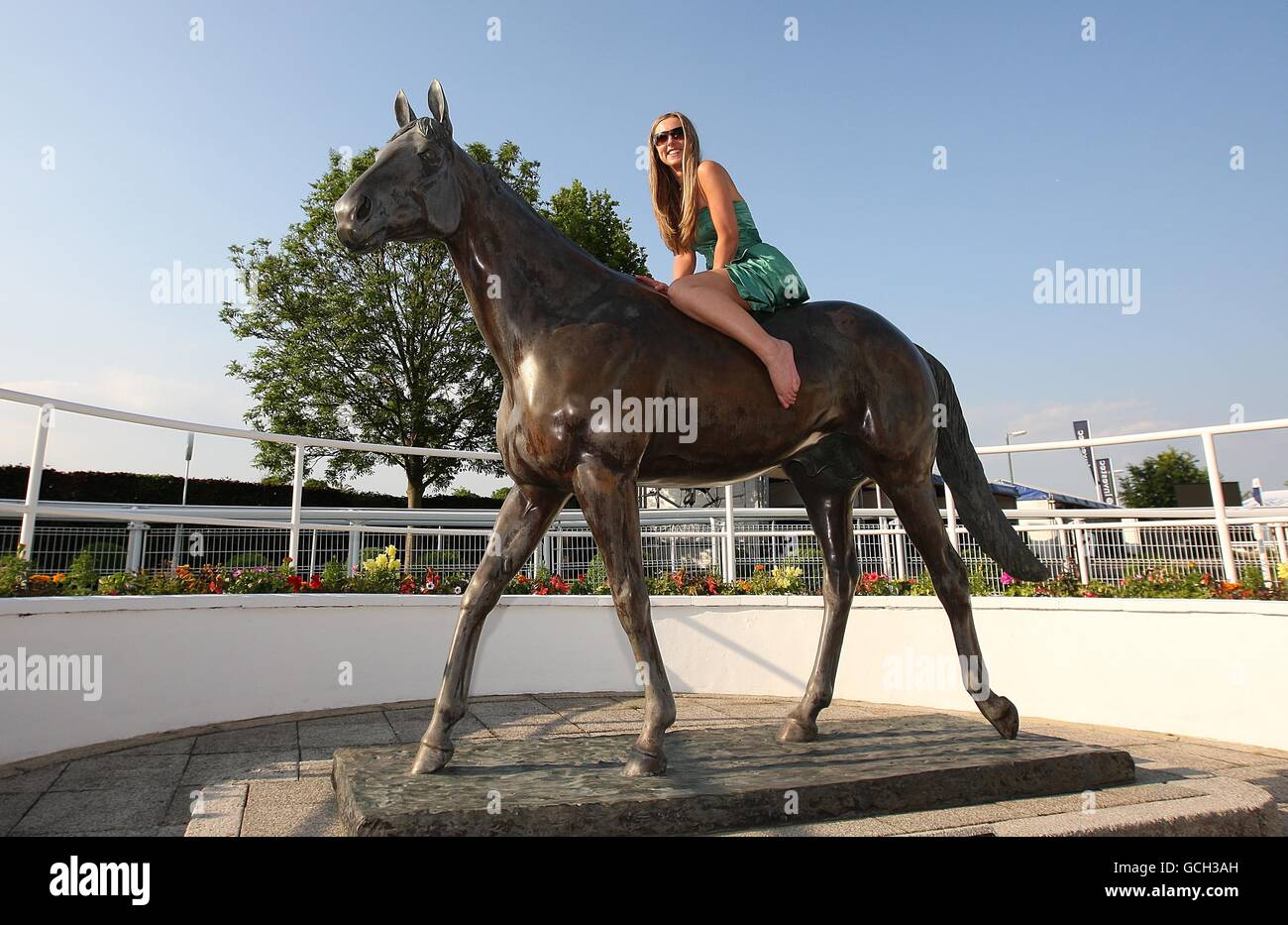 A Racegoer rides a horse statue during Ladies Day at Epsom Racecourse ...