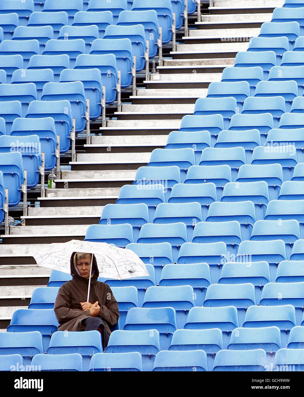 A lone fan sits in the stands as rain stops play during the AEGON ...