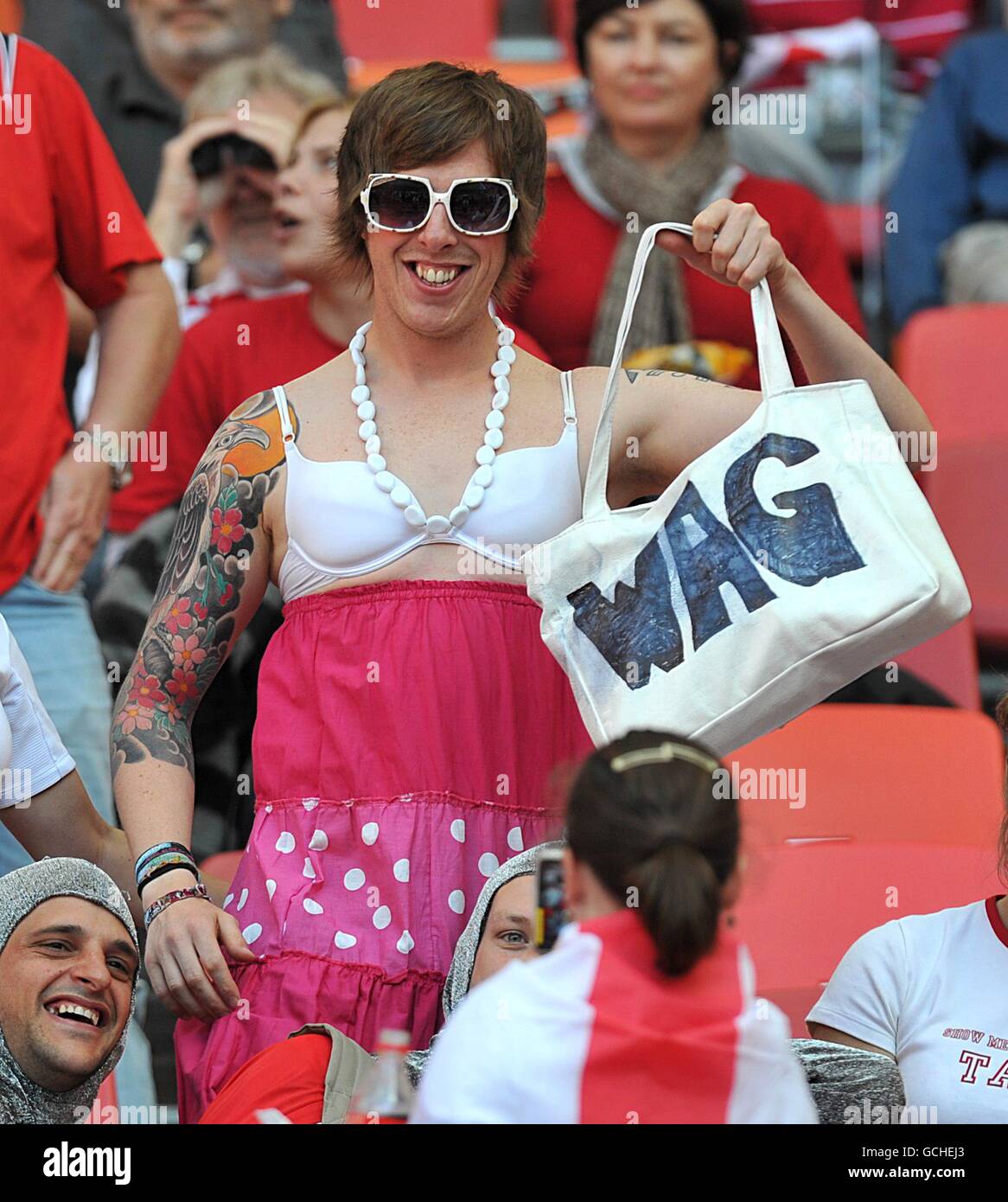 A man dressed as a lady with the word WAG written on his handbag, in ...