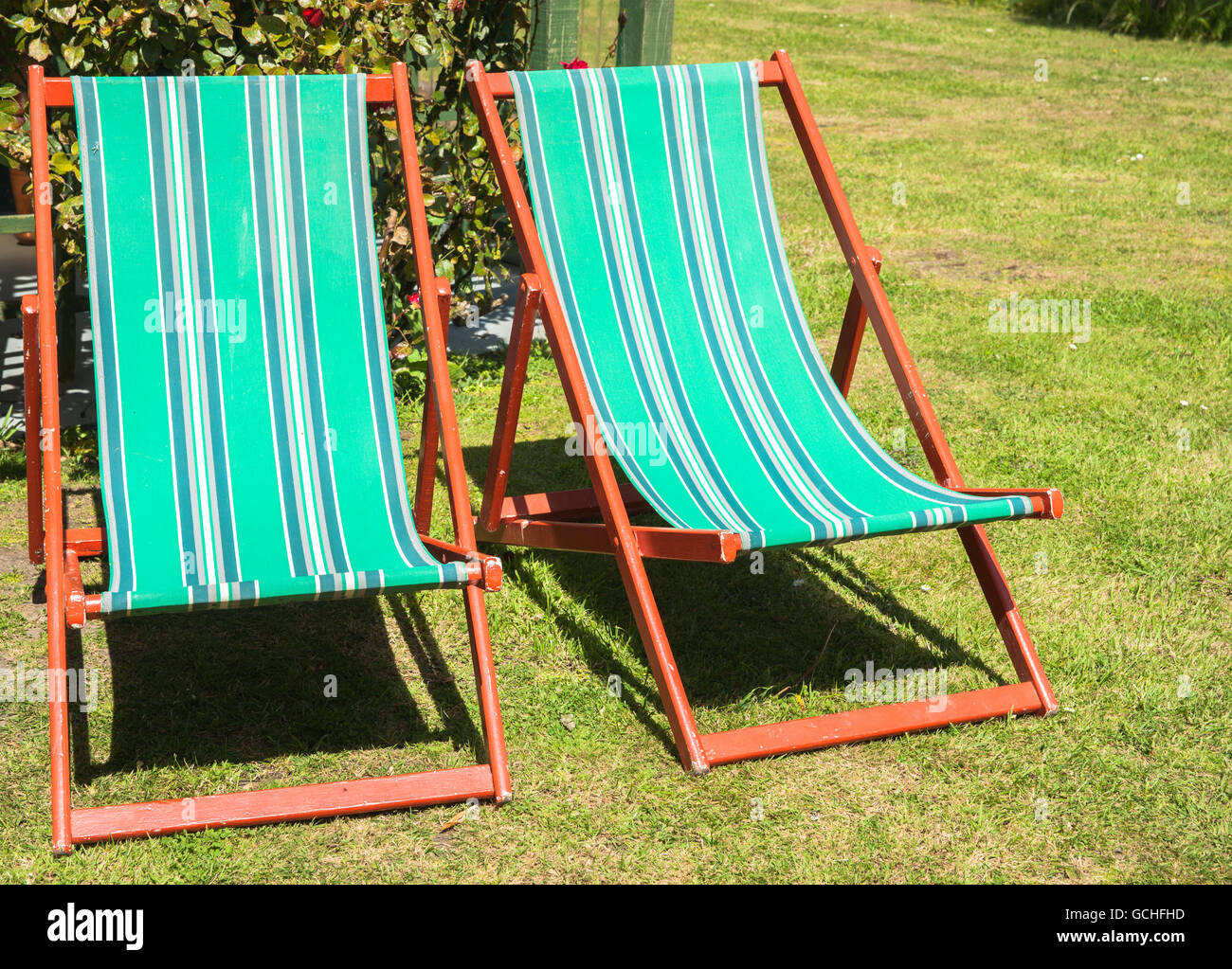 Two folding deck chairs in garden with nobody seated Stock Photo - Alamy