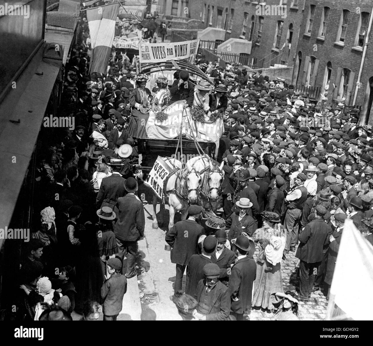 CROWDS LINE THE STREETS AS THEY WATCH SUFFRAGETTES PASS BY FOLLOWING ...