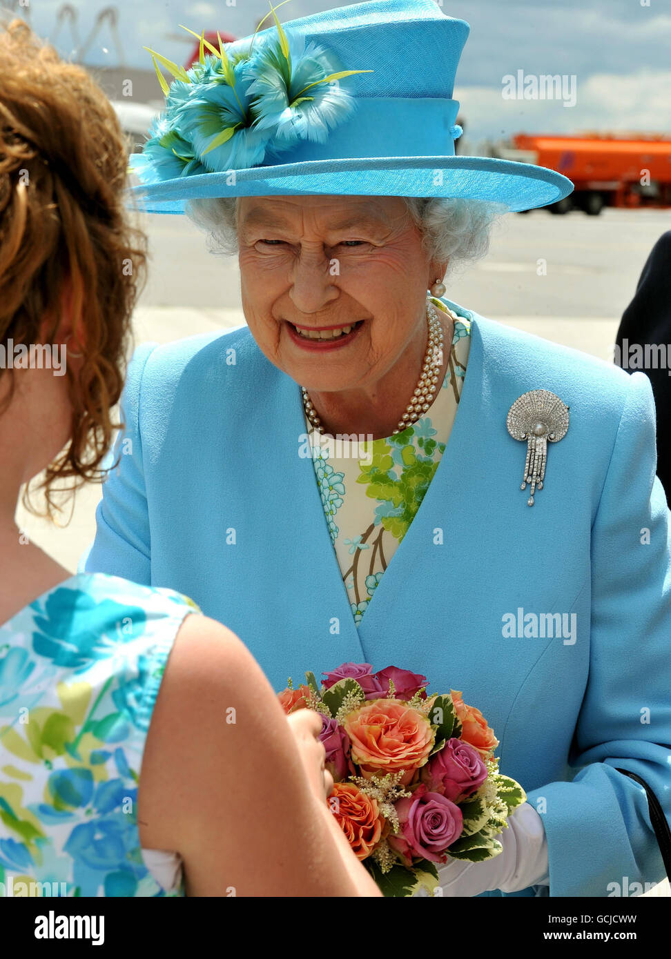 Queen Elizabeth II is presented with a posy of flowers by a young girl ...