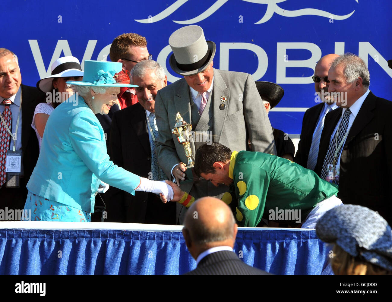 Britain's Queen Elizabeth II presents the winner's trophy to jockey ...