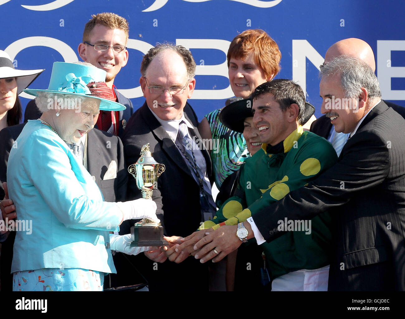 Britain's Queen Elizabeth II presents the winner's trophy to jockey ...