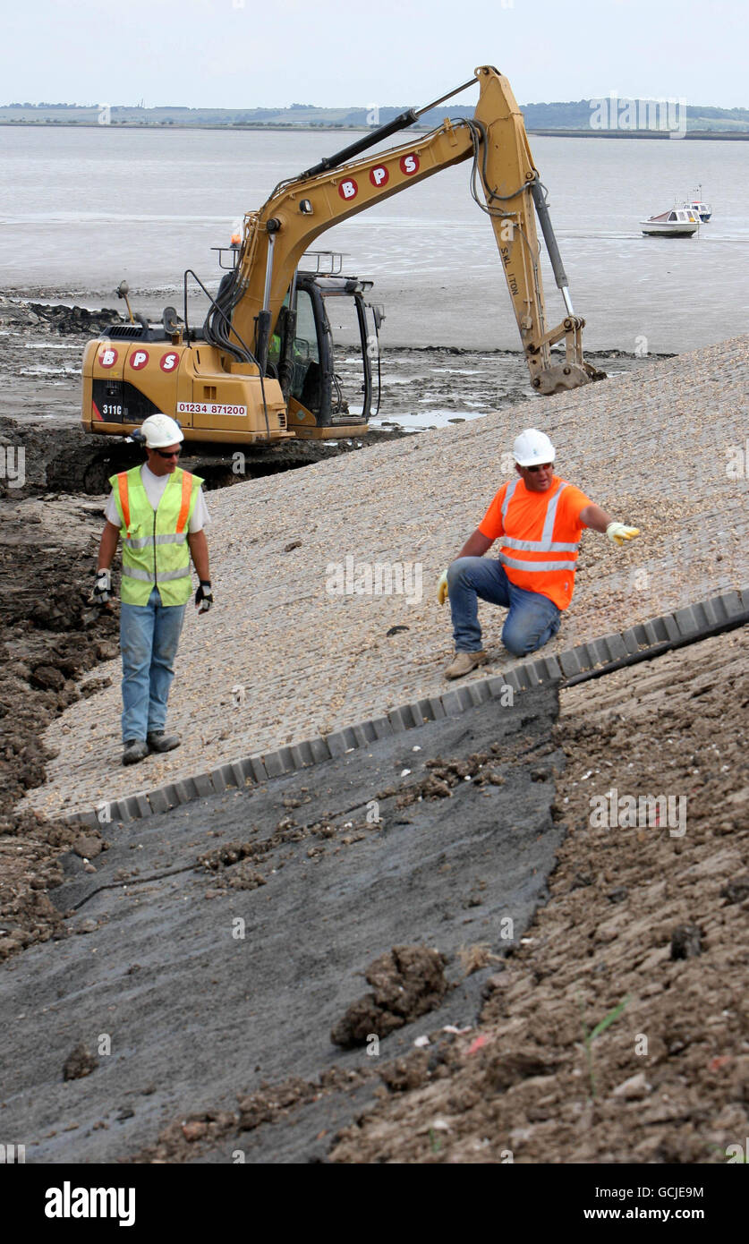 Construction workers carry out works ahead of the high tide along the ...