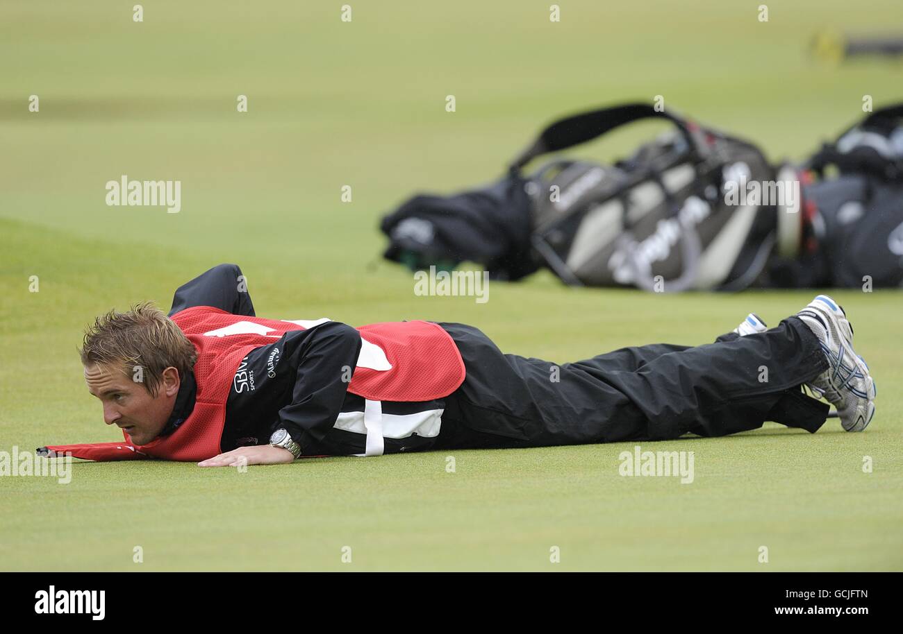 English golfer Robert Rock's caddie Jamie Lane lines up a put during ...