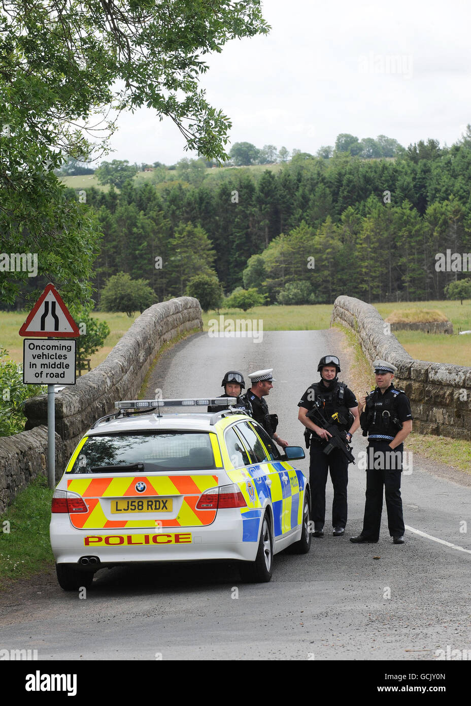 Arrmed police officers guard a bridge in the countryside outside ...