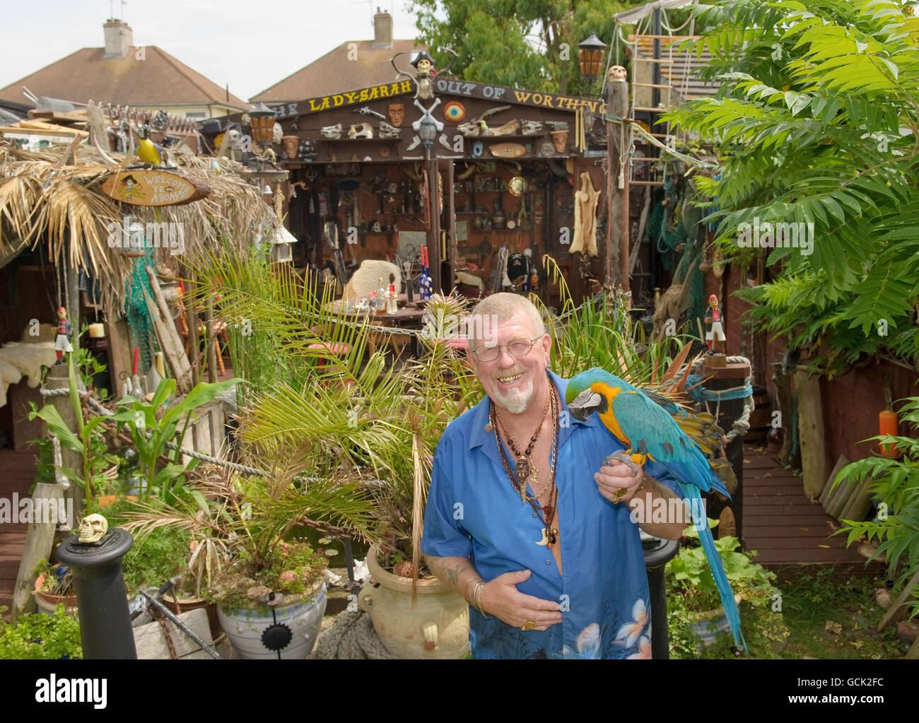 Reg Miller with Duffy, his pet parrot, outside his pirate-themed shed ...