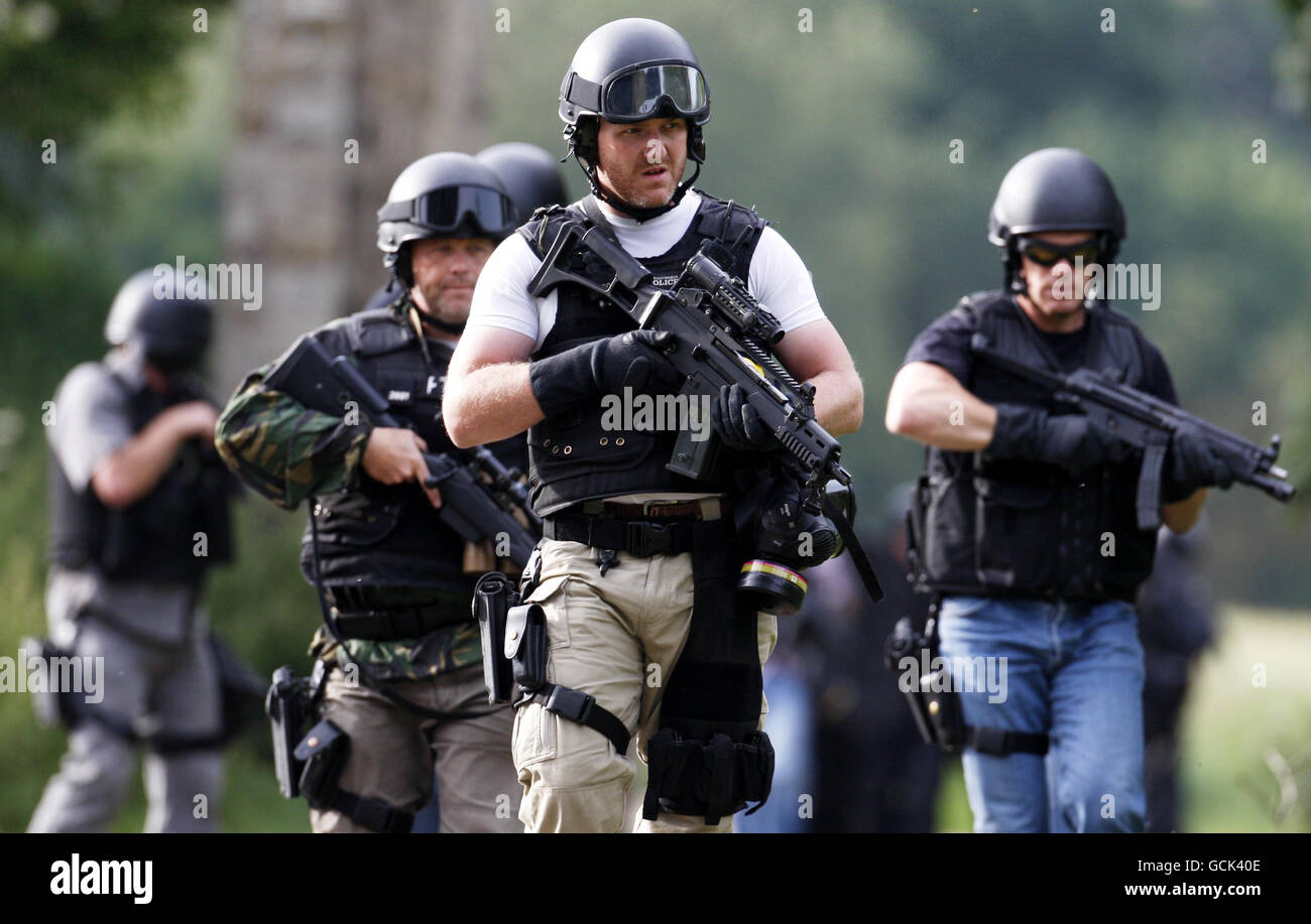 Armed police surround a man, hidden from view, as they escort him near ...
