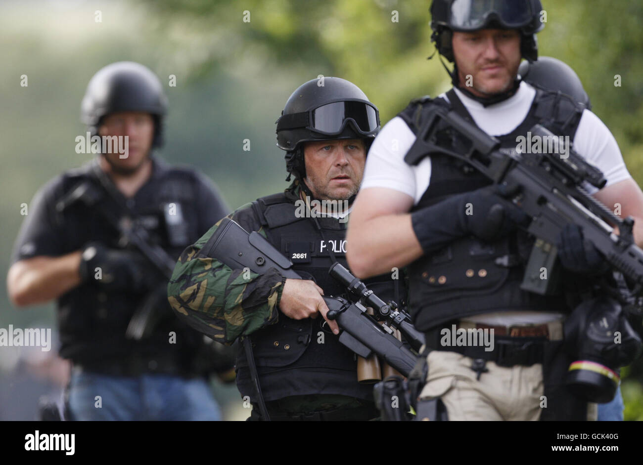 Armed police surround a man, hidden from view, as they escort him near ...