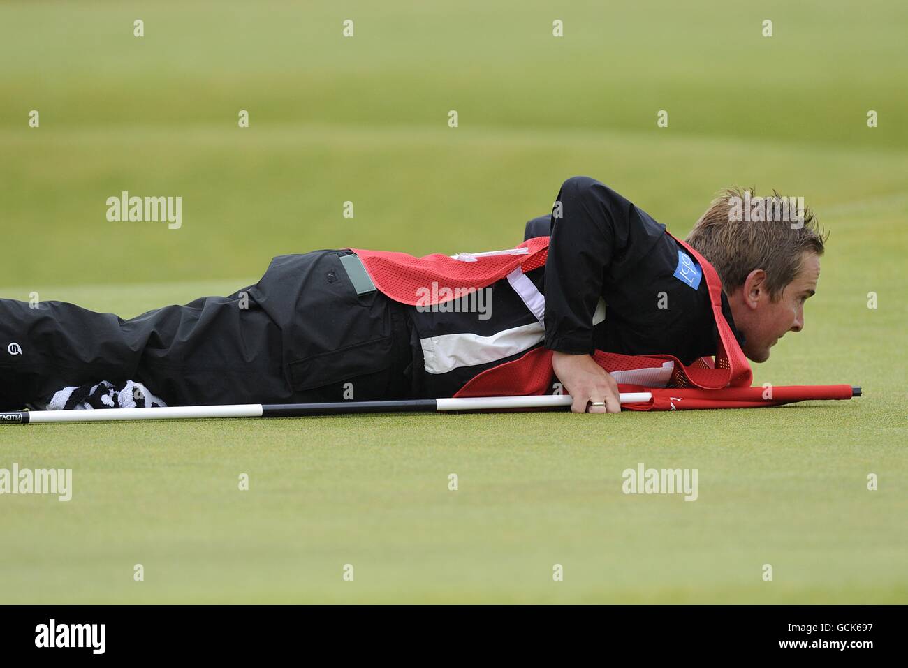 English golfer Robert Rock's caddie Jamie Lane lines up a put during ...