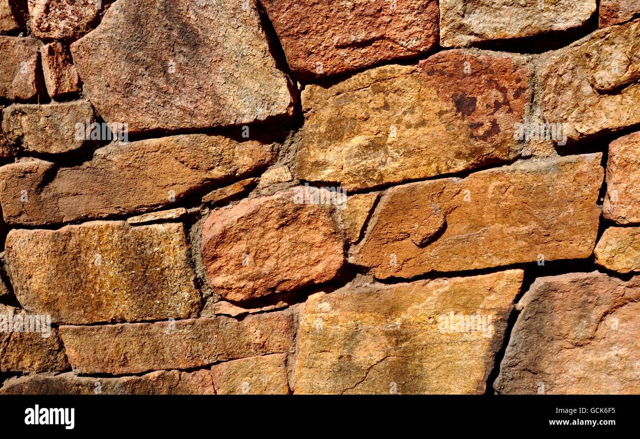 Closeup of rust colored rock boundary wall in outdoor garden setting ...