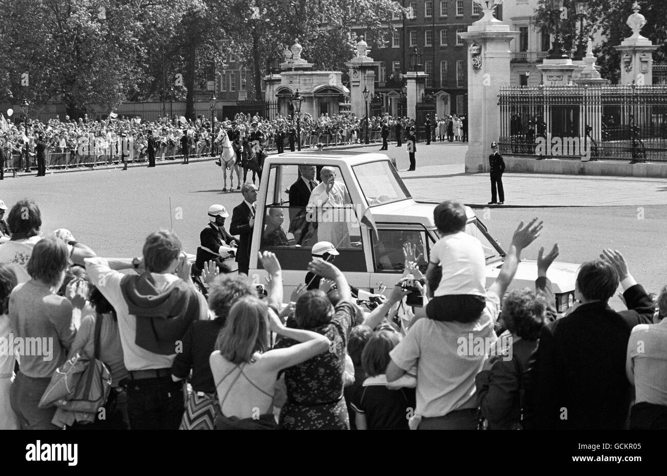 Pope John Paul II waves from the 'Popemobile' to the waiting crowds as ...
