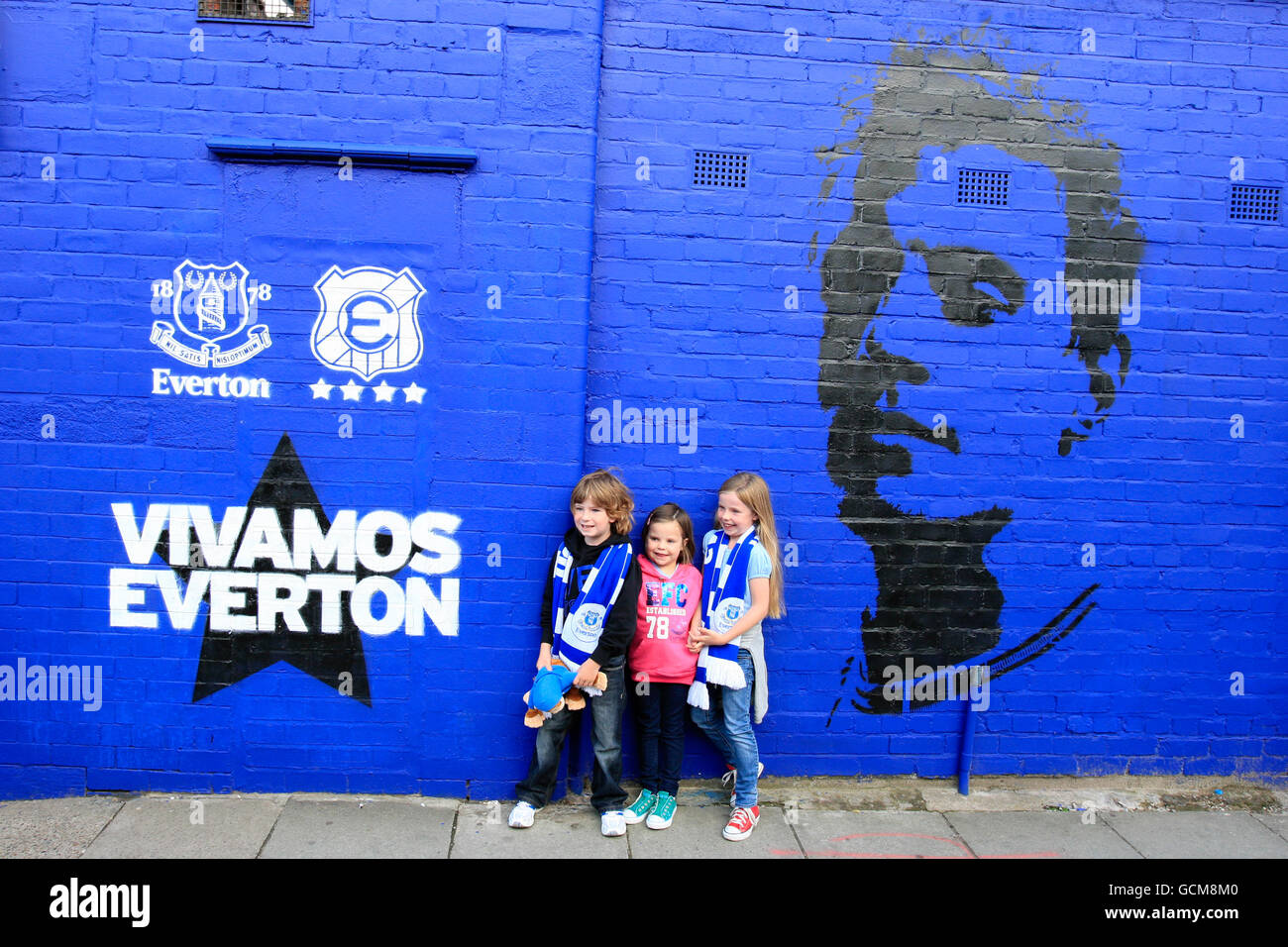 Fans pose for photographs next to a wall specially spray painted for ...