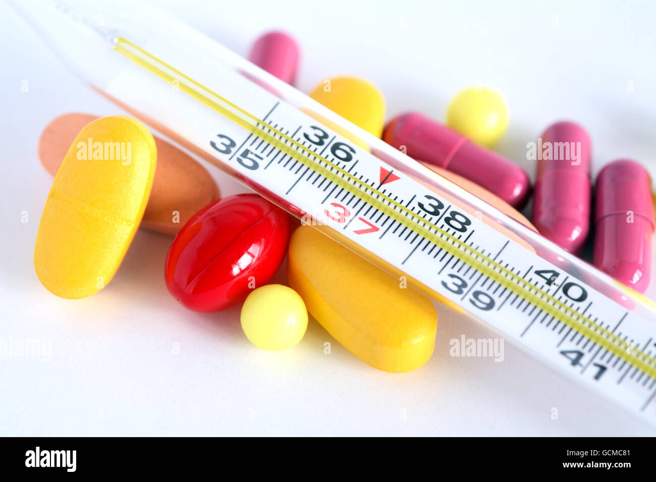 Closeup of various pills set near temperature gauge on white background ...