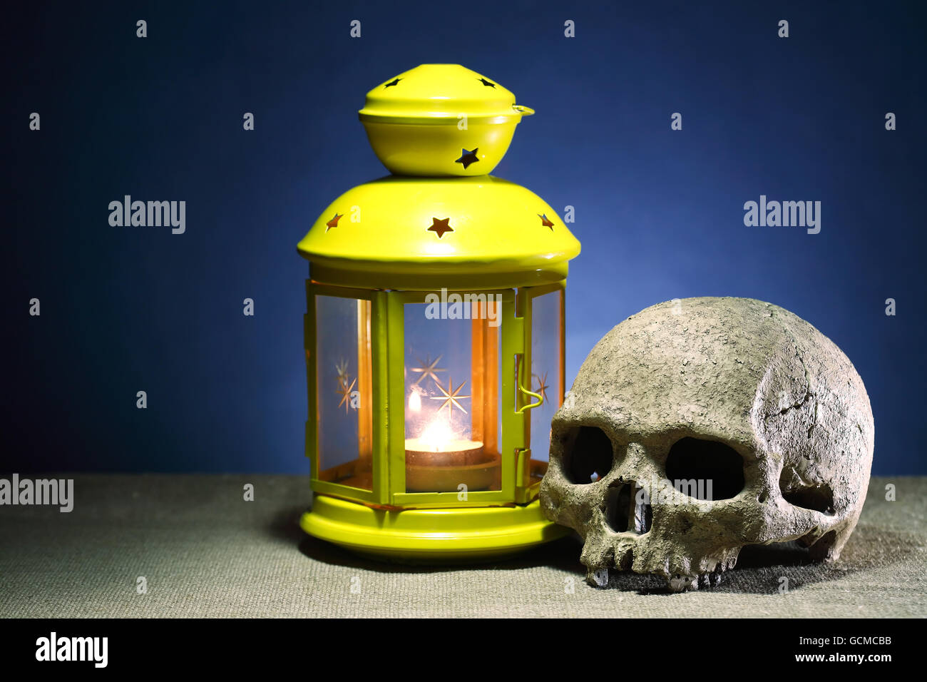 Death concept. One human skull near lighting lantern on dark background ...