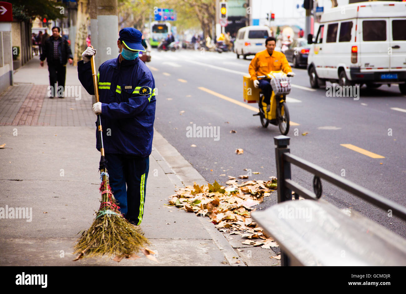 BEIJING CHINA Street sweeper in orange work wear walks on the street ...