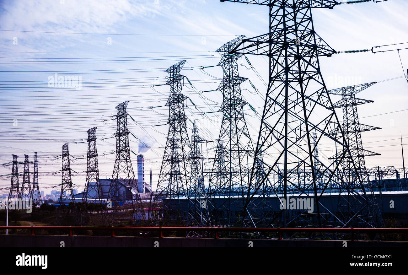 electricity transmission pylon silhouetted against blue sky at dusk ...