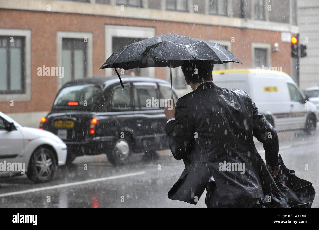 A man dashes across the street in London in a sudden heavy downpour ...