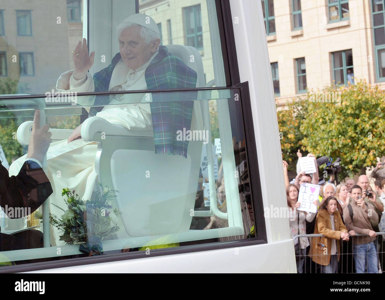Pope Benedict XVI waves at protesters holding placards in Lothian Road ...