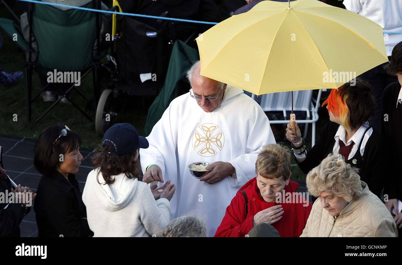A priest gives Holy Communion during a mass at Bellahouston Park in ...