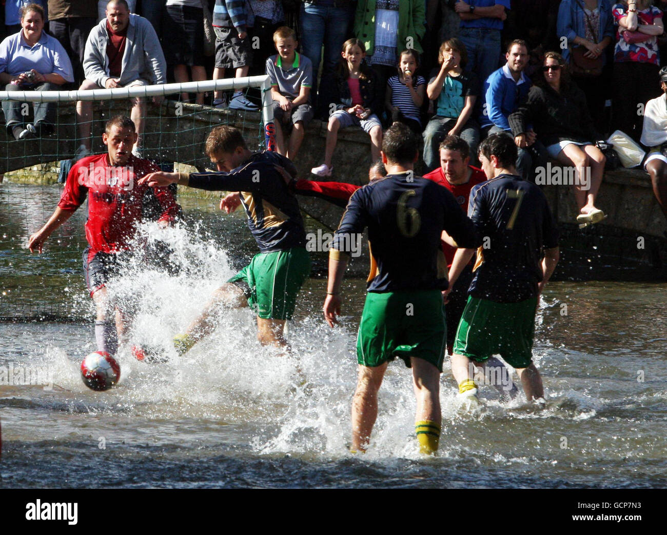 Players during the annual river football match in the River Windrush ...
