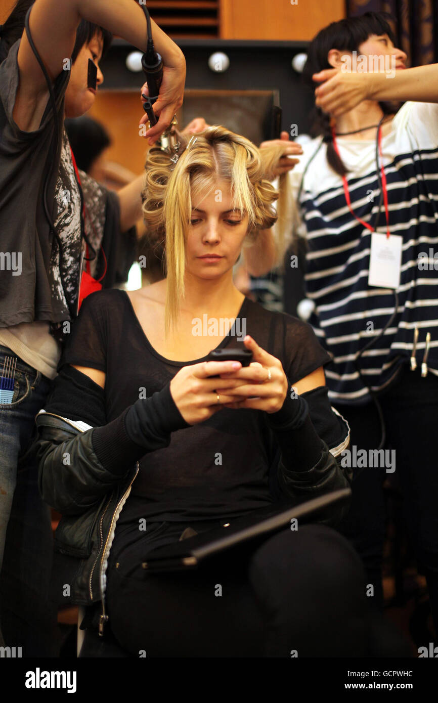 A model uses a mobile phone as she gets ready backstage at the Vivienne ...