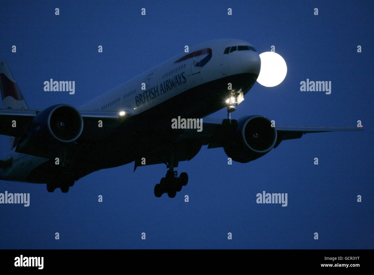 A full moon shines in the sky as a plane comes in to land at Heathrow ...