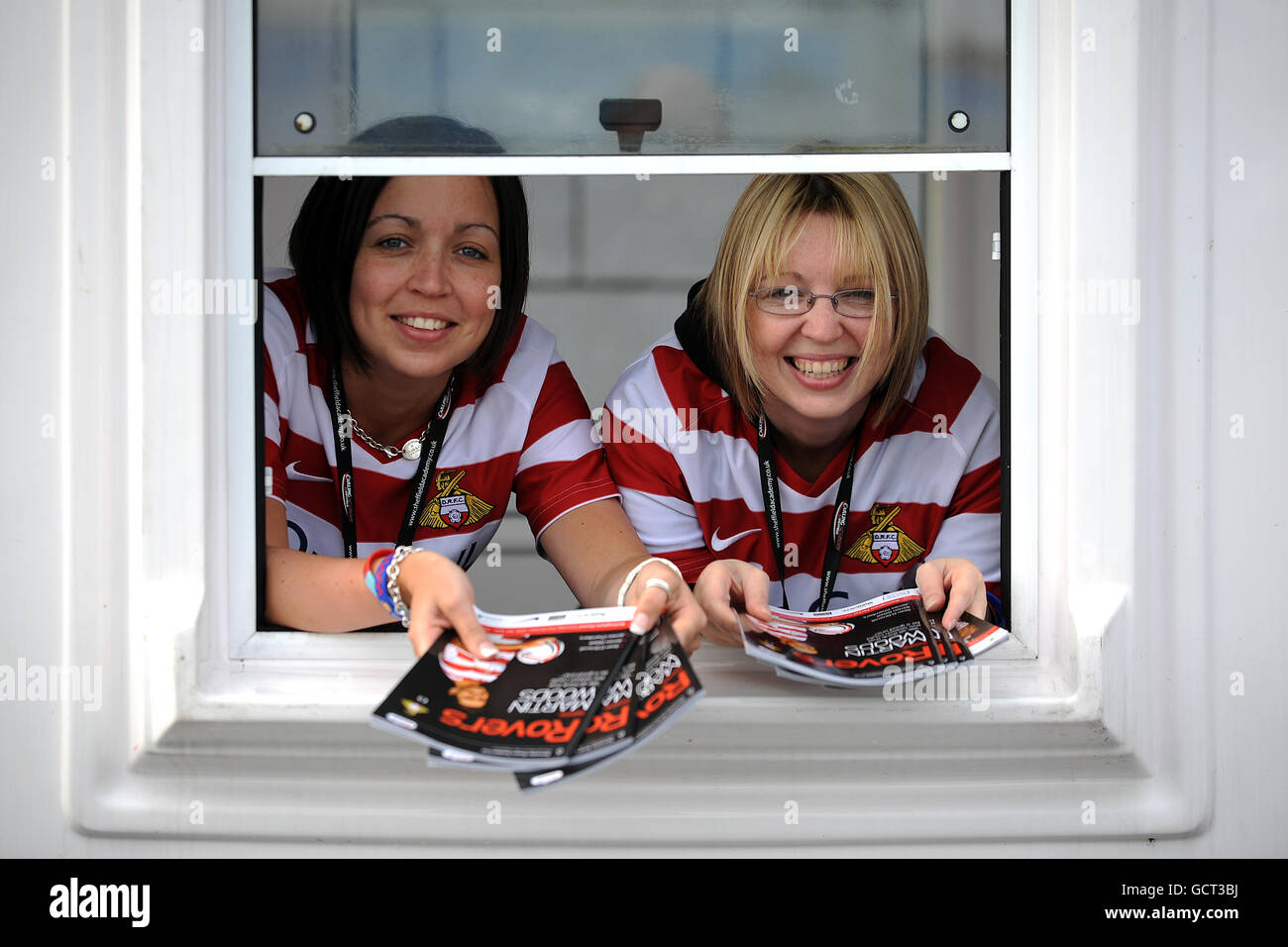 Two ladies sell Doncaster Rovers matchday programmes from a booth ...