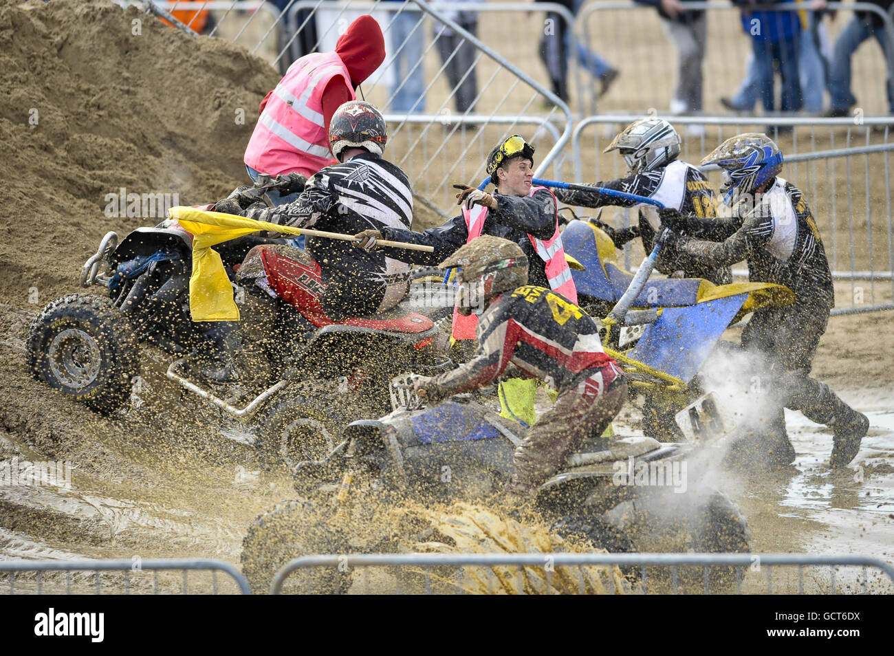 A race marshal is showered in sand and mud as competitors bunch up at ...