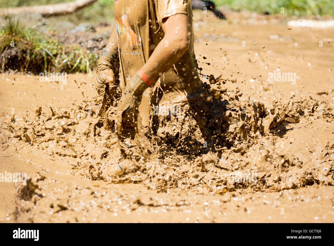 A participant is jumping into muddy water at an extreme sport challenge ...