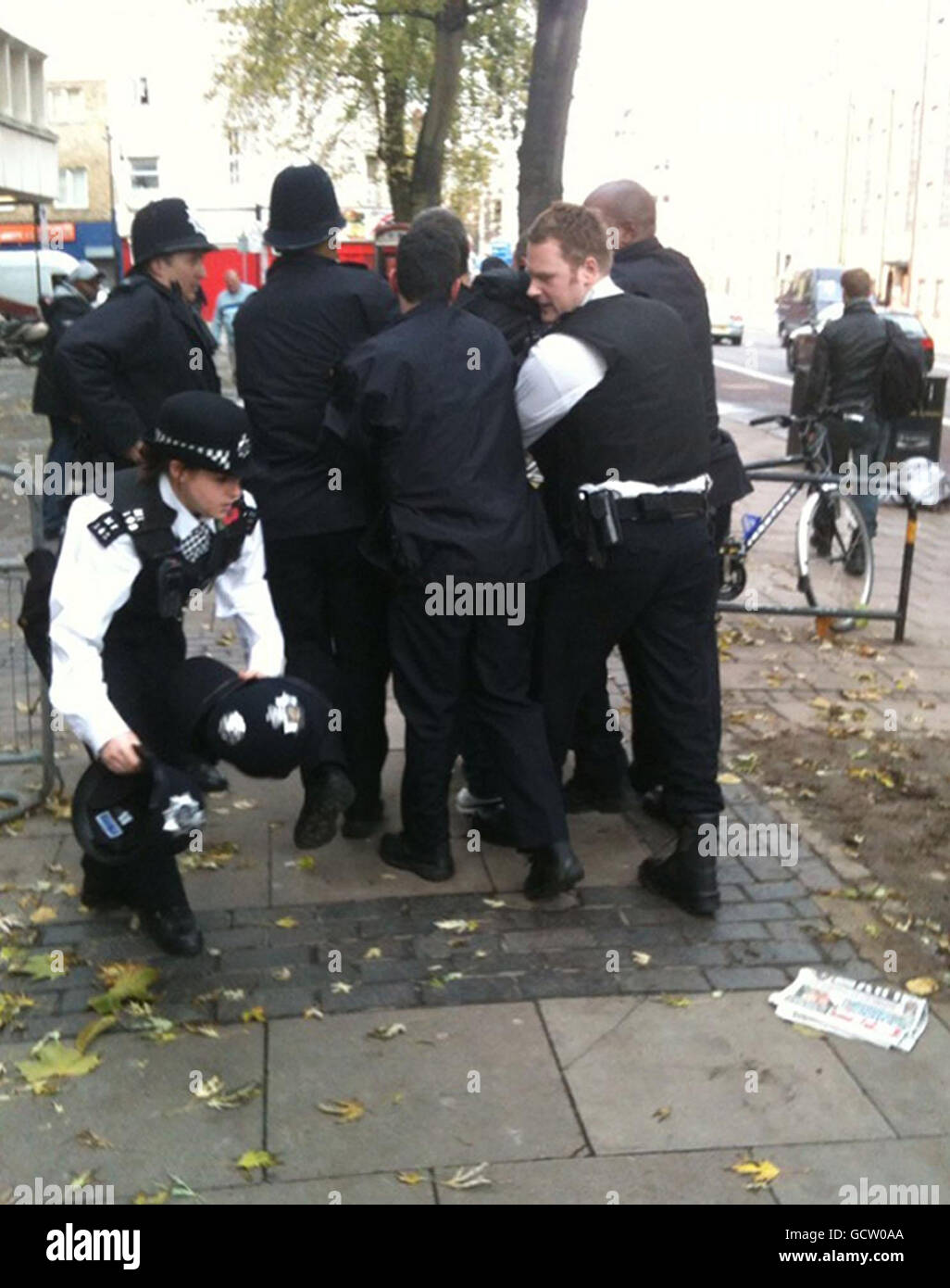 Police officers restrain a a grey-haired man in his 40s outside ...
