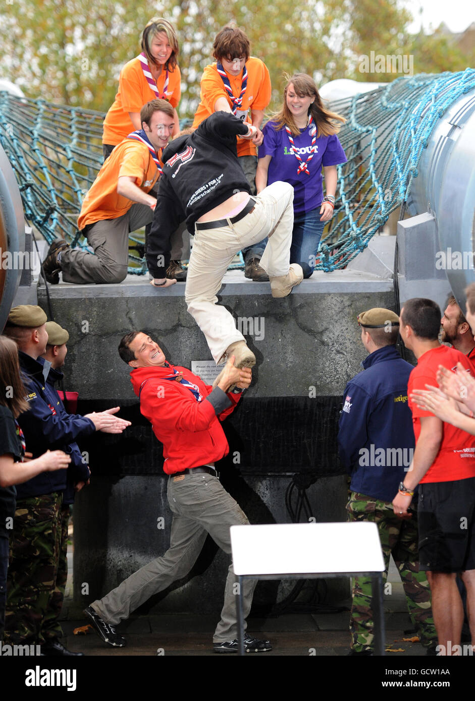 Prince Harry (black top) is helped up by Bear Grylls (left) as Scouts ...