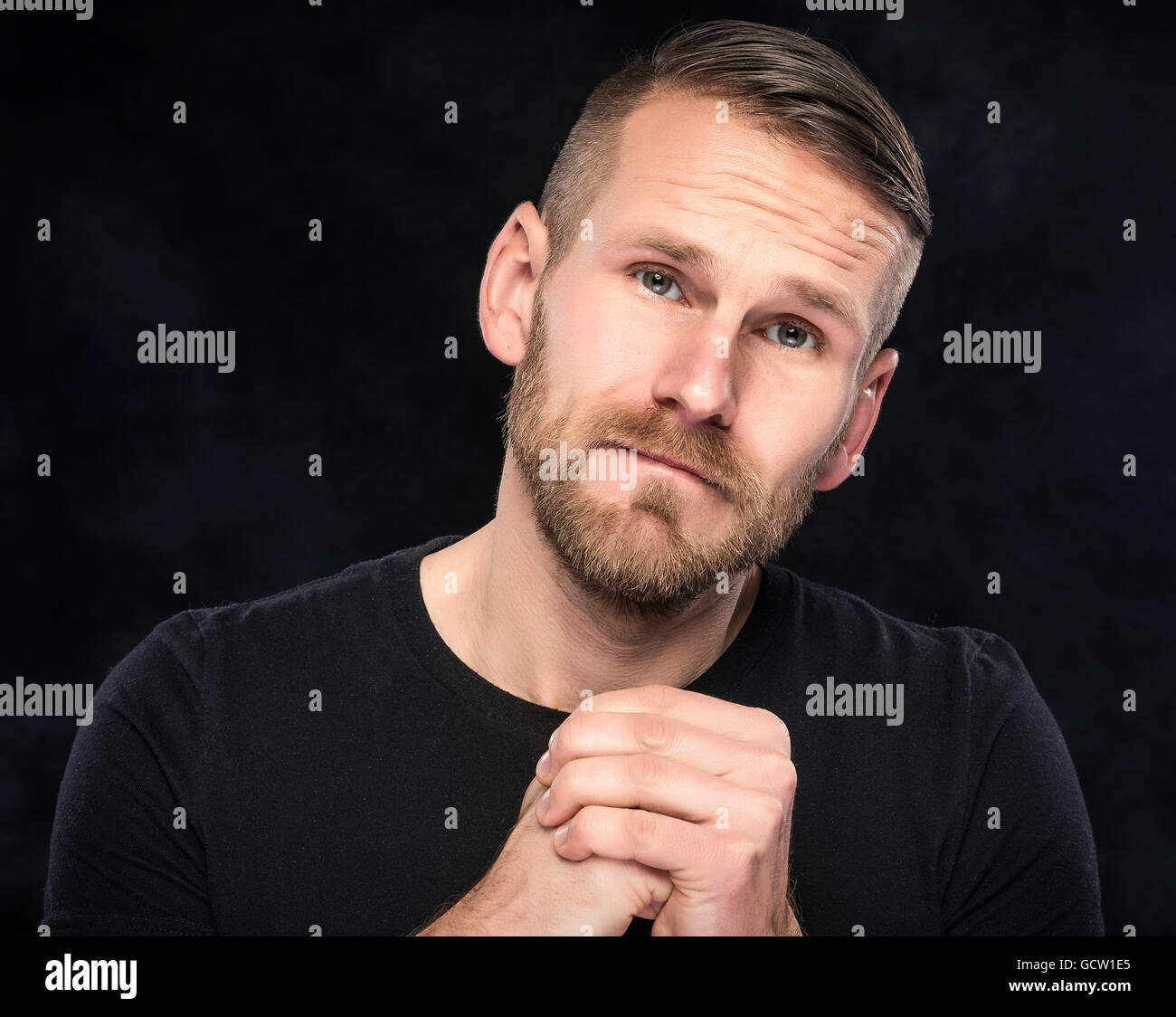 Young man asks for forgiveness on a dark background Stock Photo - Alamy