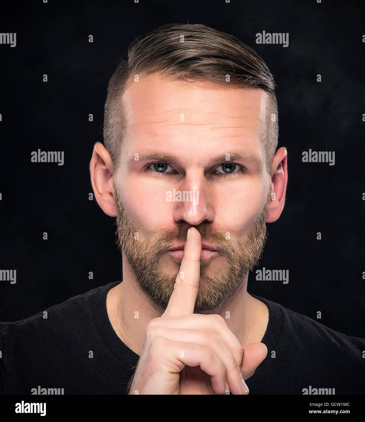 Man gesturing silence, quiet, on dark background Stock Photo - Alamy
