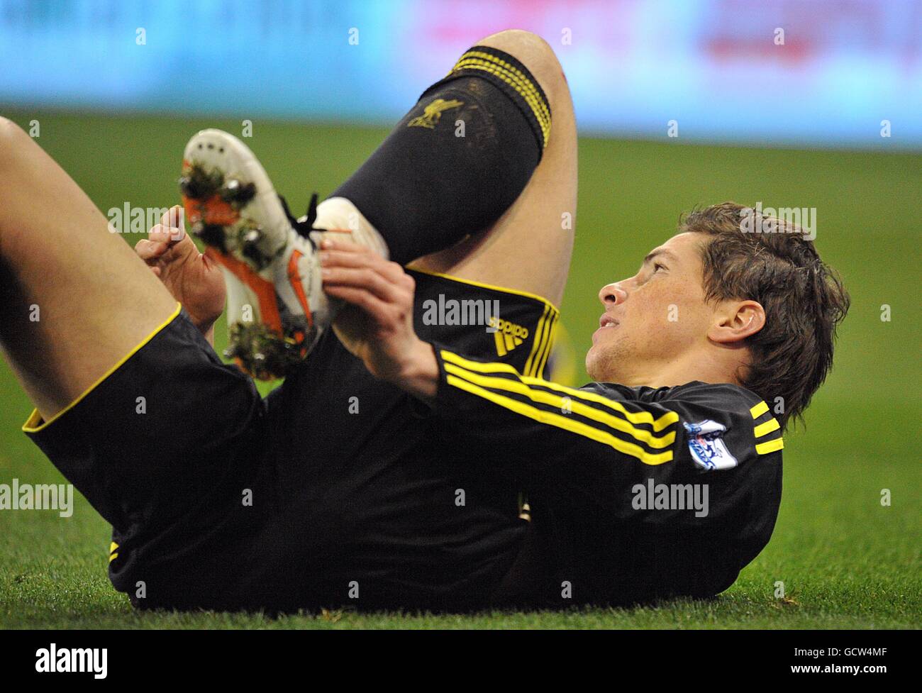 Liverpool's Fernando Torres holds his ankle as he sustains an injury ...
