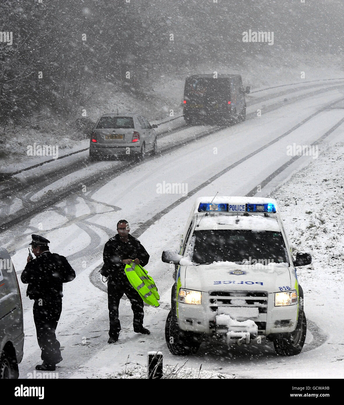 Police officers direct a gritting lorry as a road over the North ...
