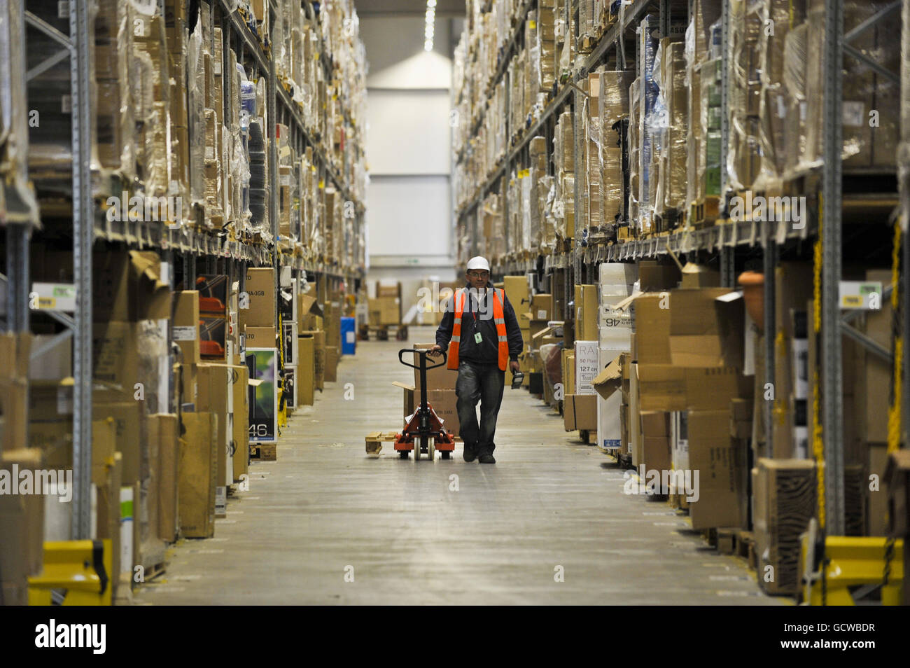 An Amazon worker walks down a huge storage aisle full of goods at the ...