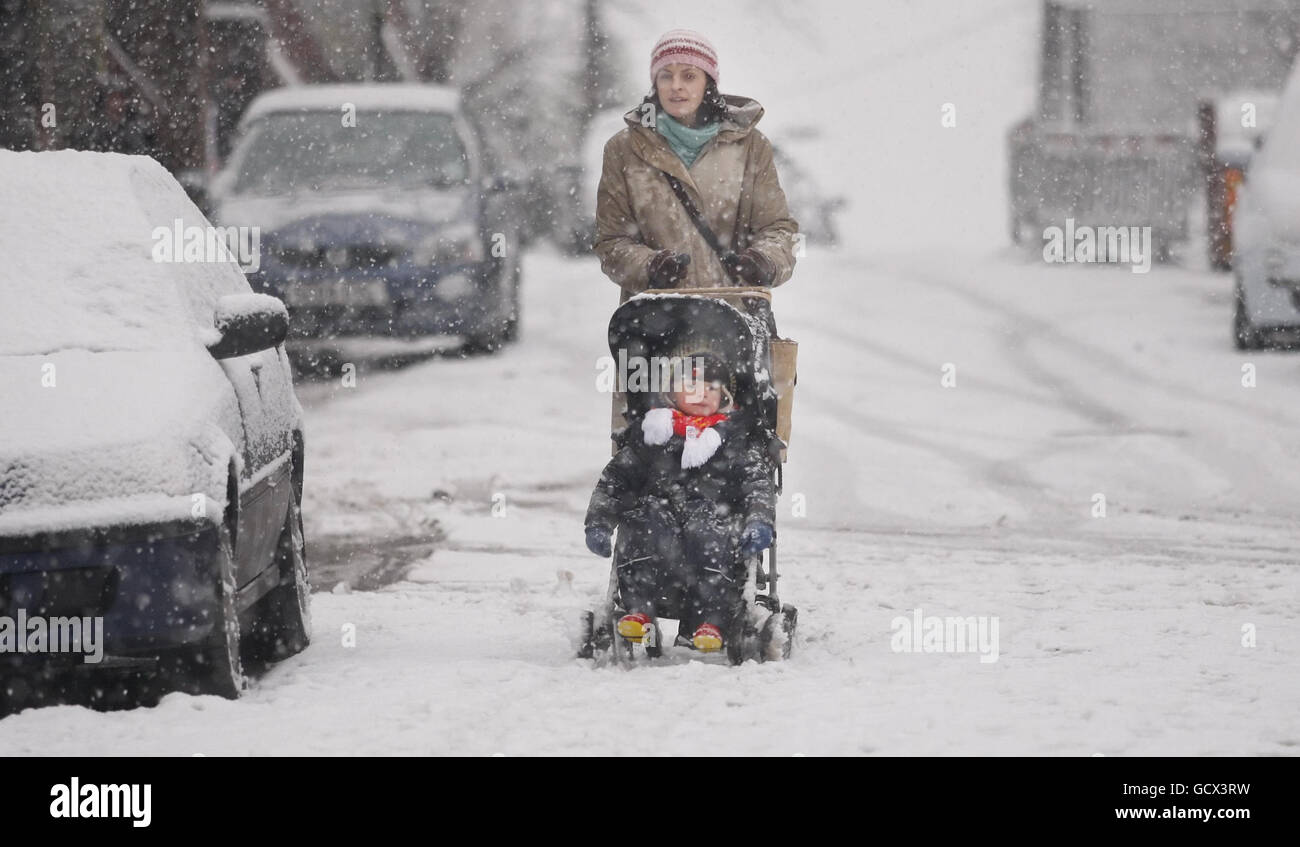 A woman pushing a child in a pushchair makes her way through fresh snow ...