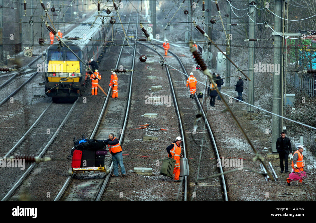 Workmen take suitcases off a train stranded outside Huntingdon Railway ...
