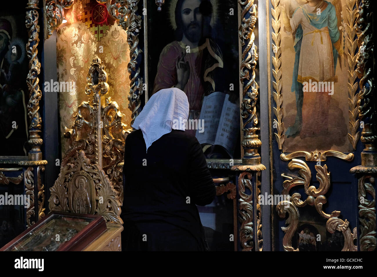 A Romanian woman praying inside St. Antony's Orthodox Church, known as ...