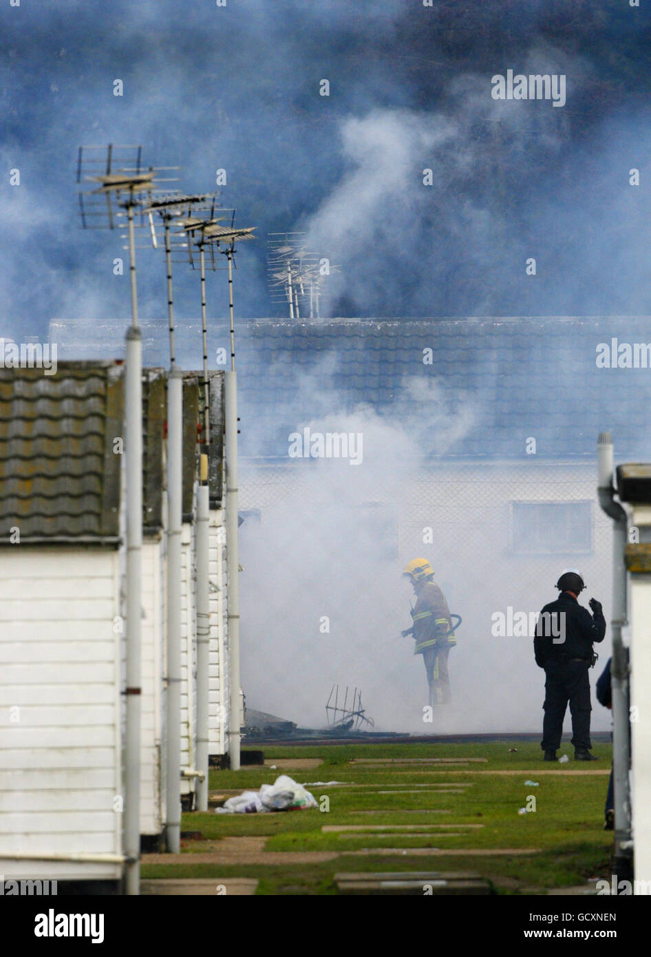 Fire fighter dampens down fire at hmp ford near arundel hi-res stock ...