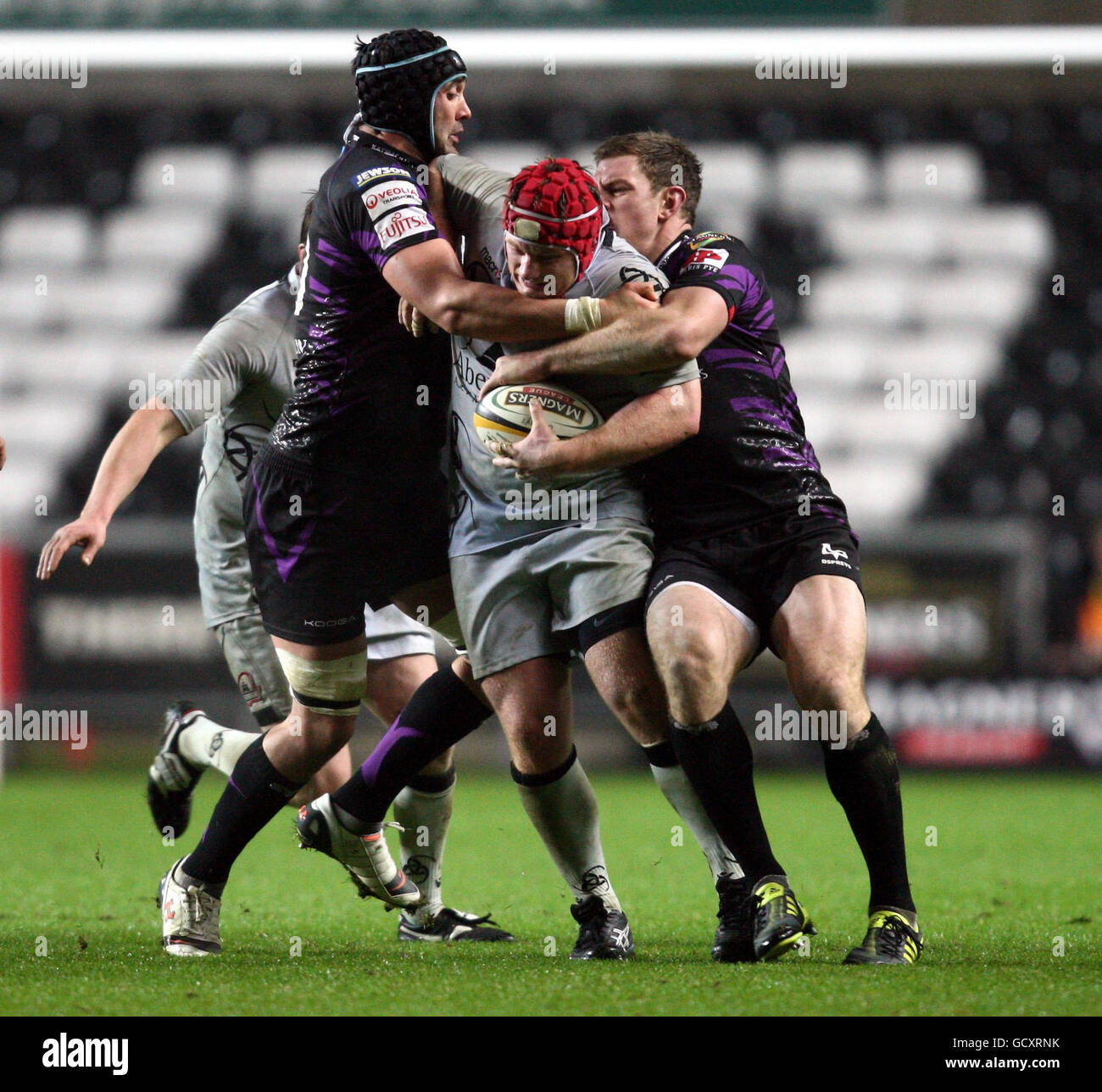 Edinburgh's Kyle Traynor is tackled by Ospreys' Jonathan Thomas and Dan ...